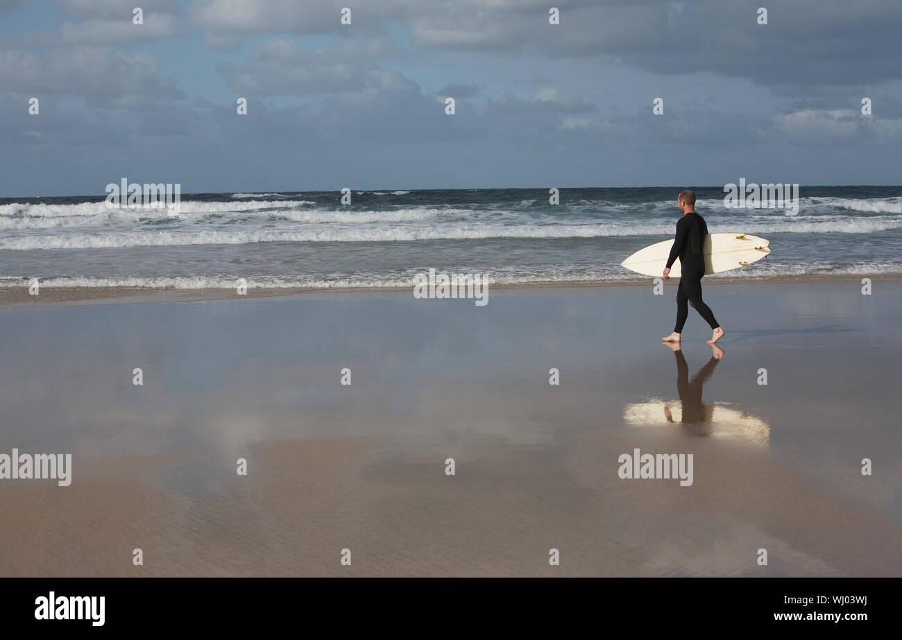 Side view of man with surfboard walking towards ocean Stock Photo - Alamy