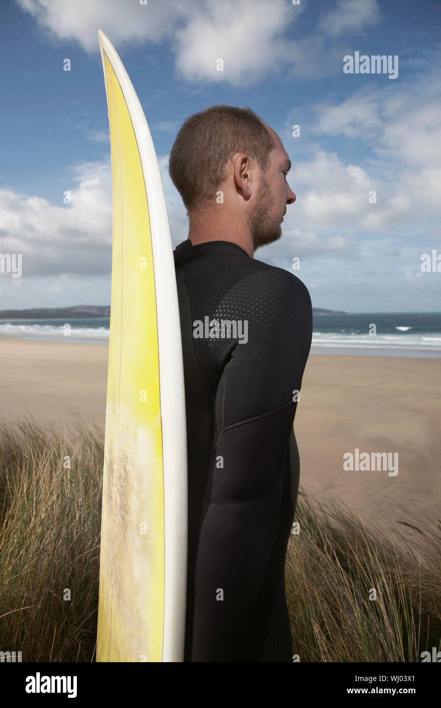 Side view of man with surfboard standing on beach Stock Photo - Alamy