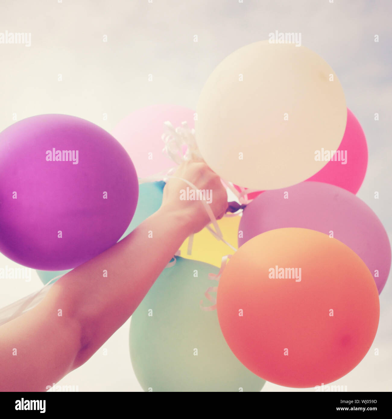 Hand holding multicolored balloons with retro filter effect Stock Photo ...