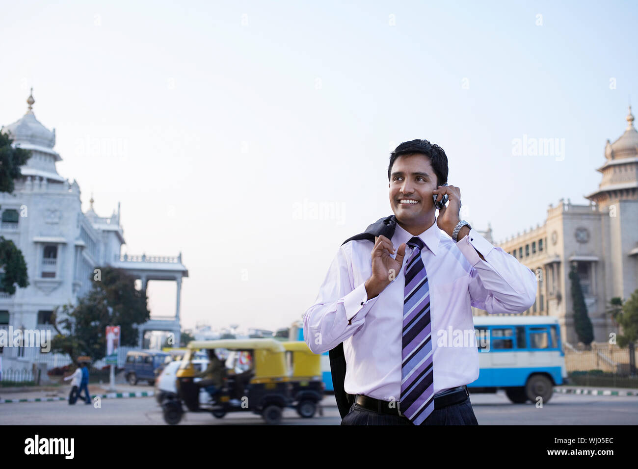 Happy young businessman using cell phone on city street Stock Photo - Alamy