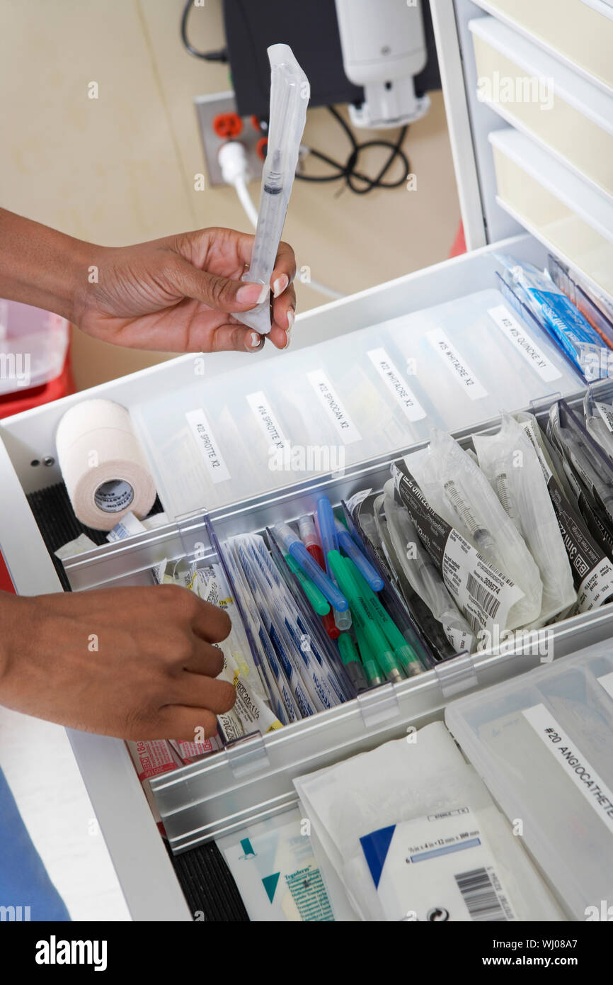 Woman taking syringe from drawer full of medical supplies, close-up of ...