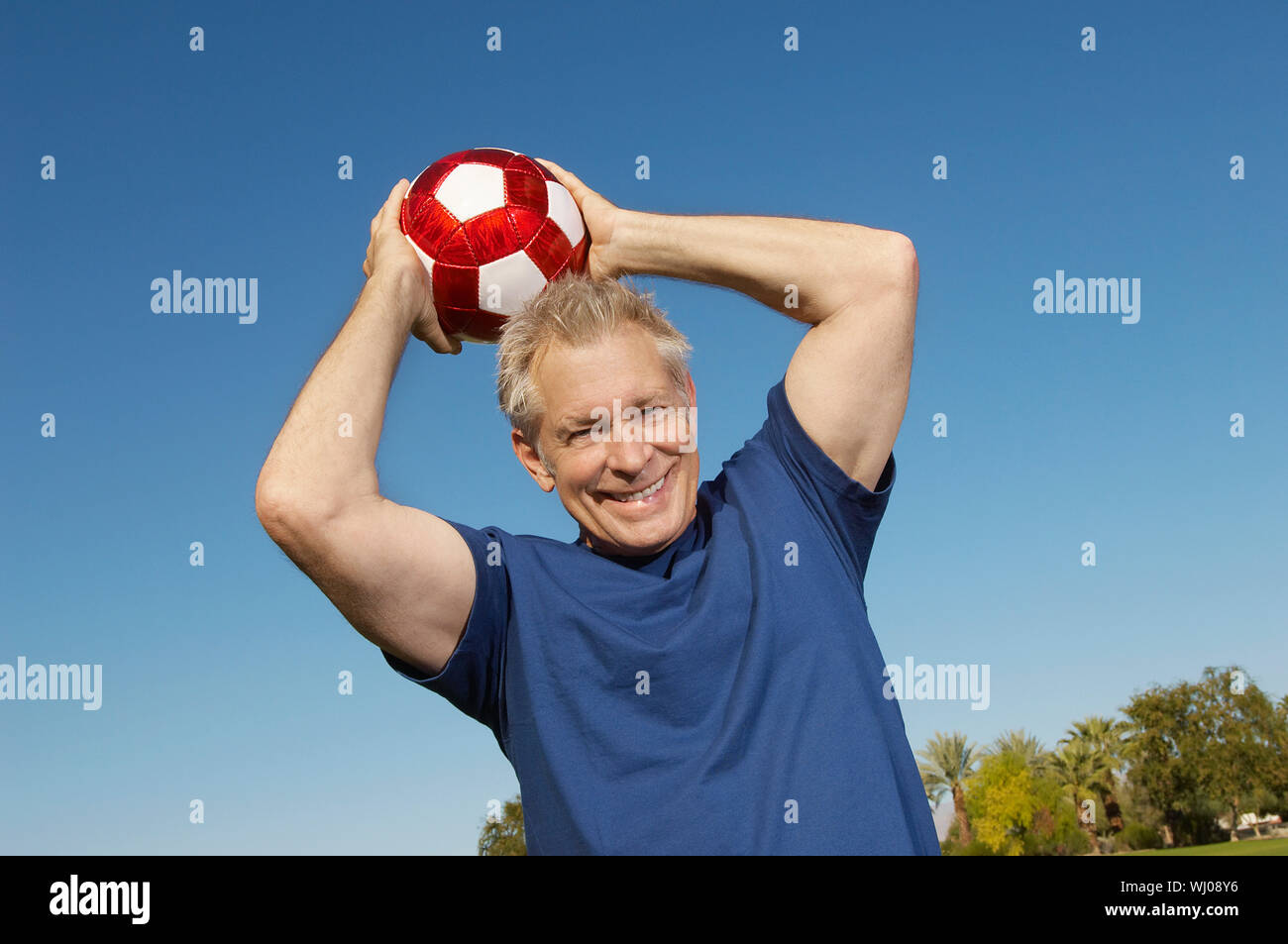 Senior man holding soccer ball over head, outdoors Stock Photo - Alamy