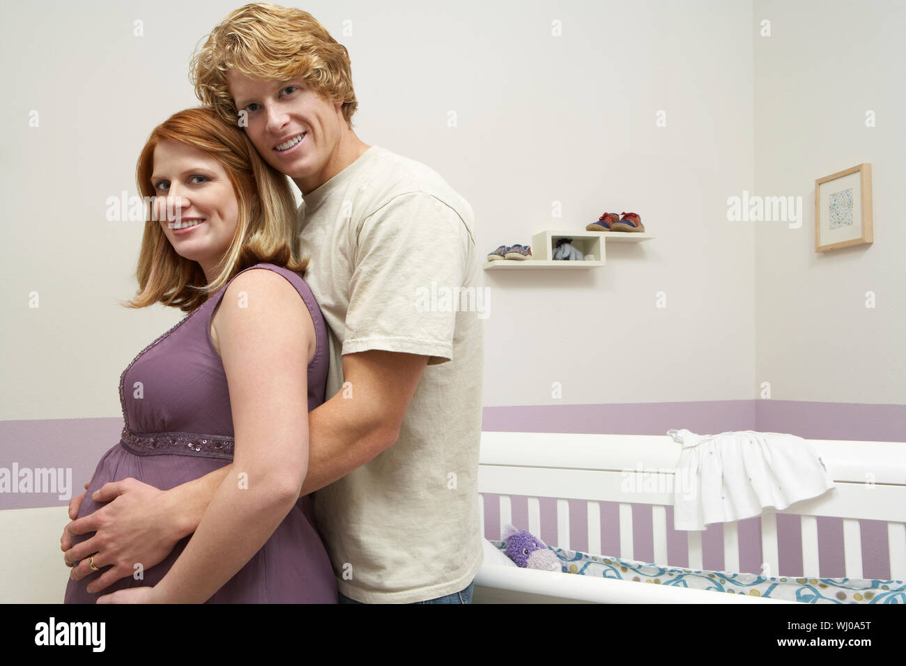 Expectant couple embracing by cradle, portrait Stock Photo - Alamy