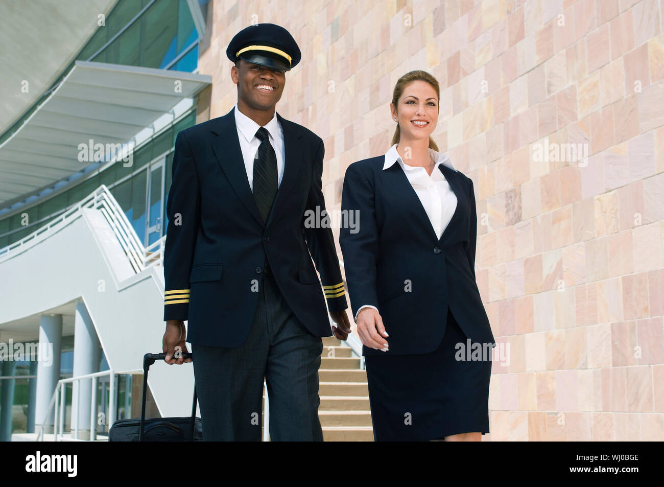 Pilot and flight attendant walking outside building Stock Photo - Alamy