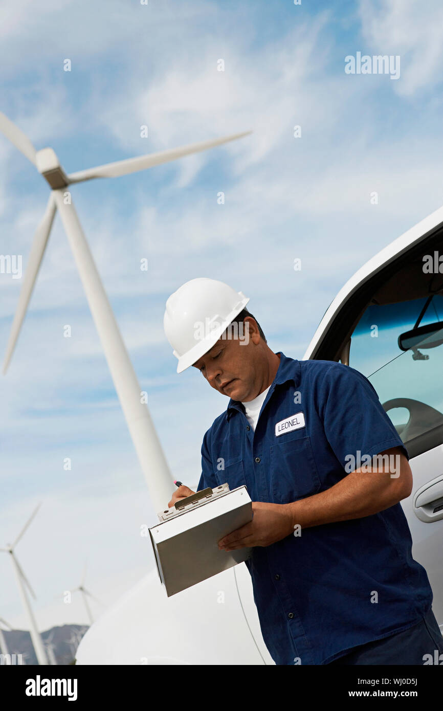 Engineer writing on clipboard by car at wind farm Stock Photo - Alamy