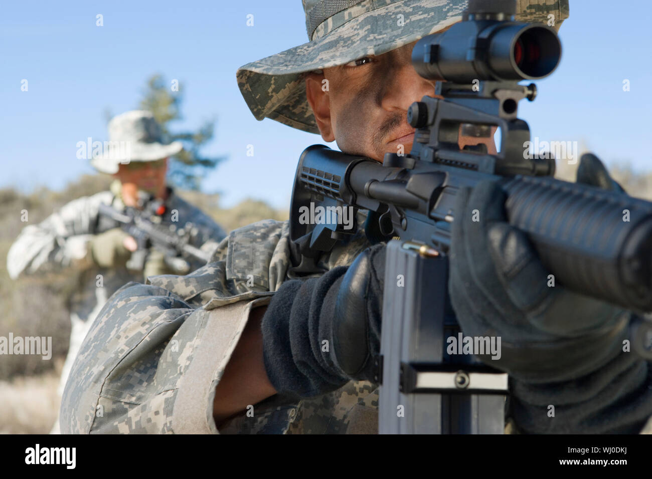 Soldiers aiming rifles in field, focus on soldier in foreground Stock ...