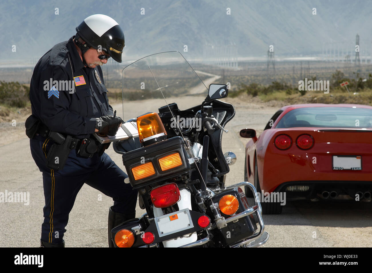 Traffic cop writing against motorcycle on country road Stock Photo - Alamy
