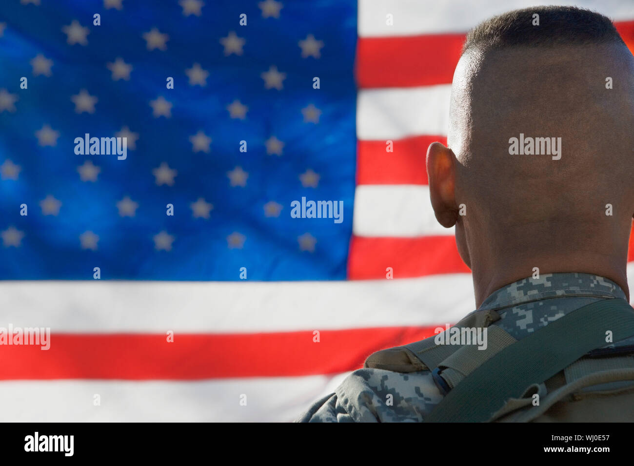 US Army soldier looking at flag, back view Stock Photo - Alamy