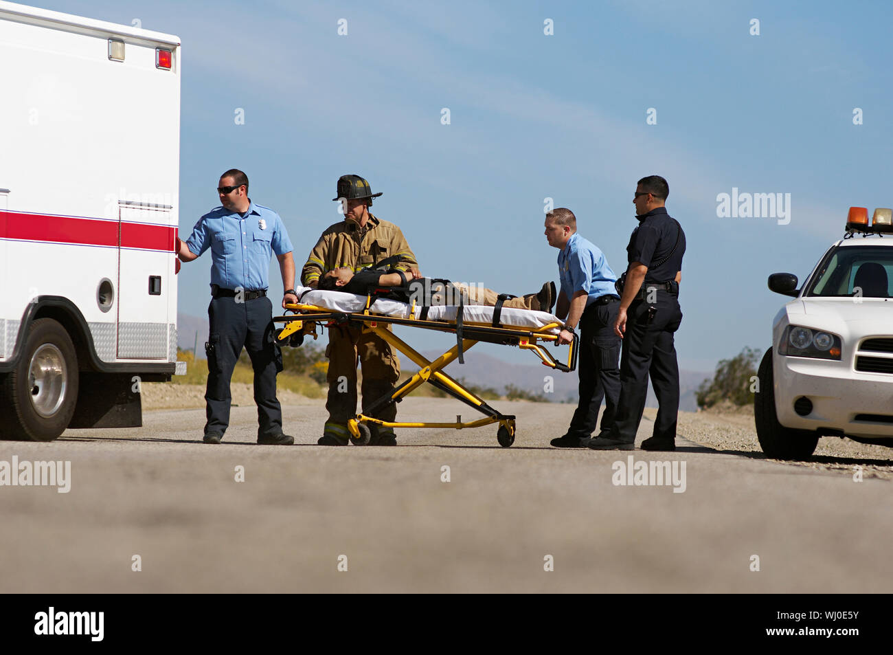 Paramedics transporting victim on stretcher Stock Photo - Alamy