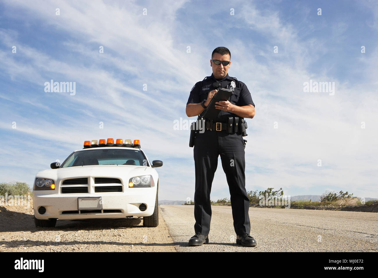 Police officer taking notes in front of police car Stock Photo - Alamy