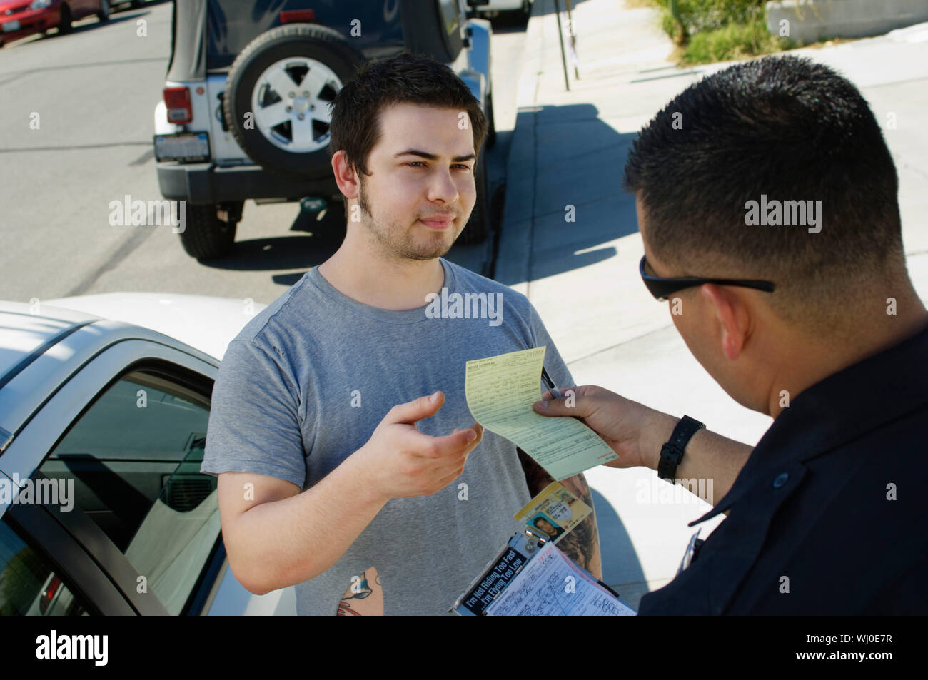 Mature police officer giving ticket to young man for breaking traffic ...