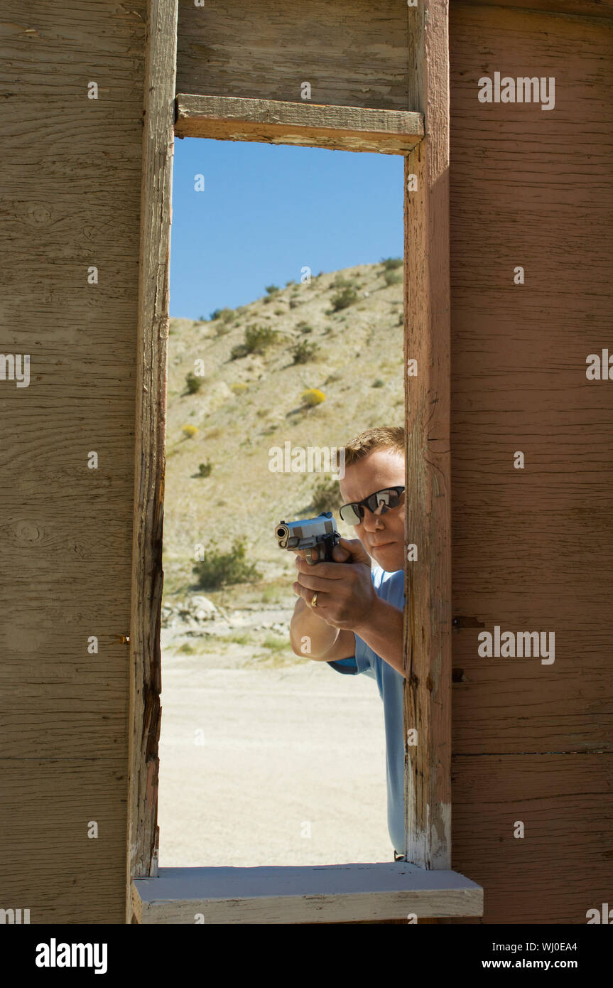 Man aiming hand gun at firing range Stock Photo - Alamy