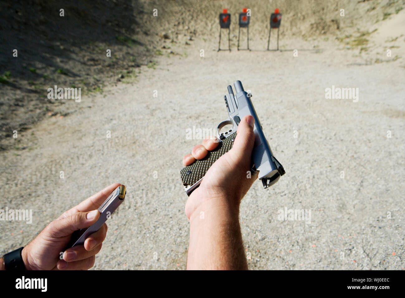 Man loading hand gun at firing range, focus on hands Stock Photo - Alamy