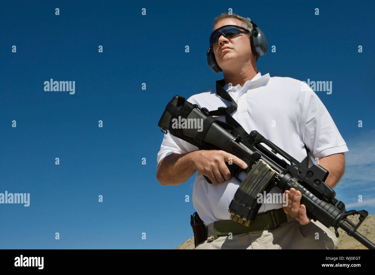 Man holding machine gun at firing range, low angle view Stock Photo - Alamy