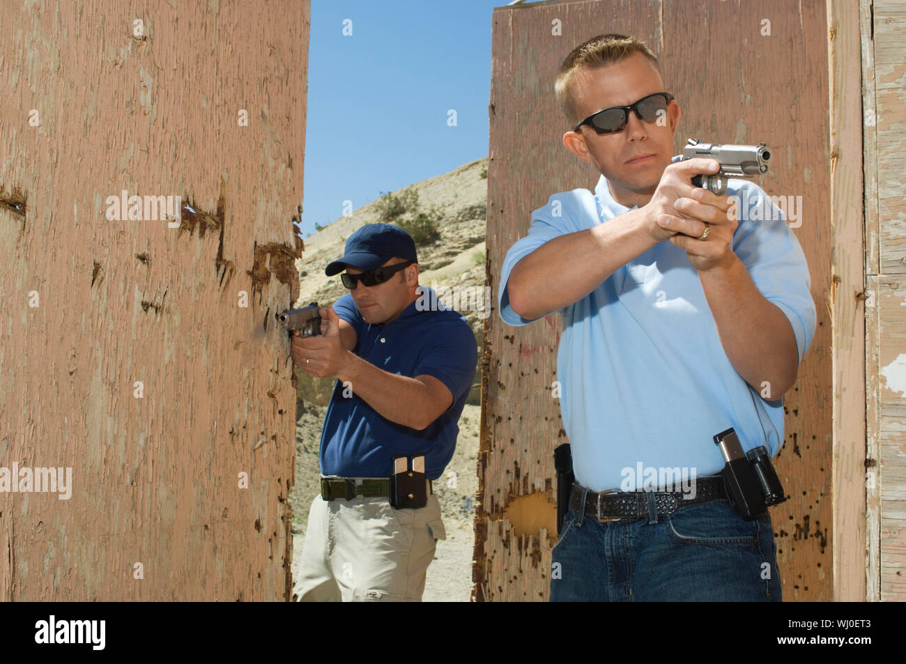 Two men aiming hand guns at firing range Stock Photo - Alamy