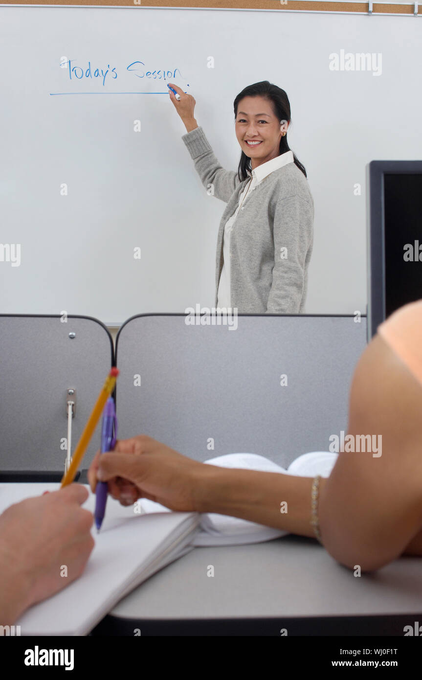 Teacher writing on whiteboard during lesson in classroom Stock Photo ...