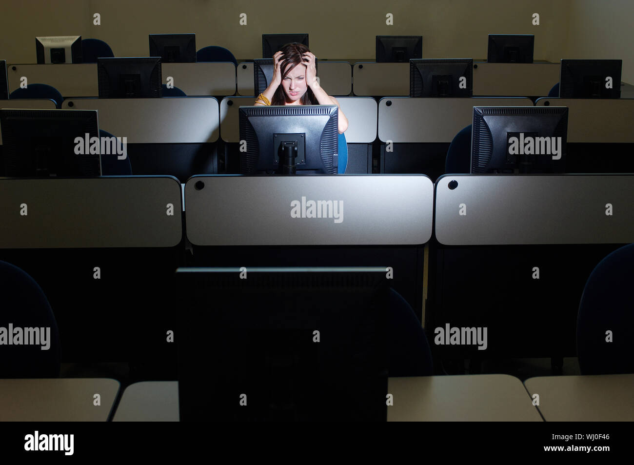 Female student with head in hands in computer classroom Stock Photo - Alamy