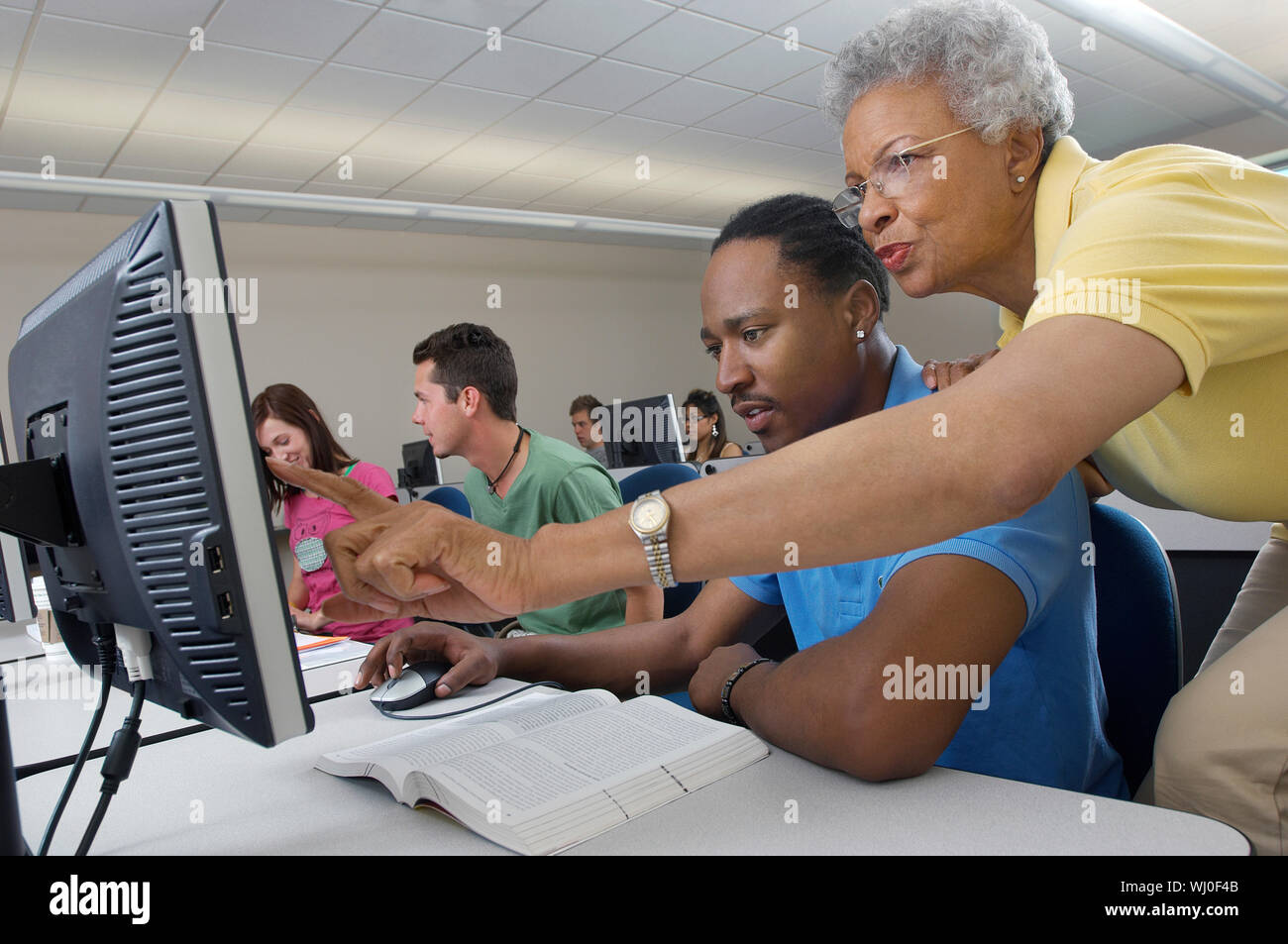 Teacher helping student in computer class Stock Photo - Alamy