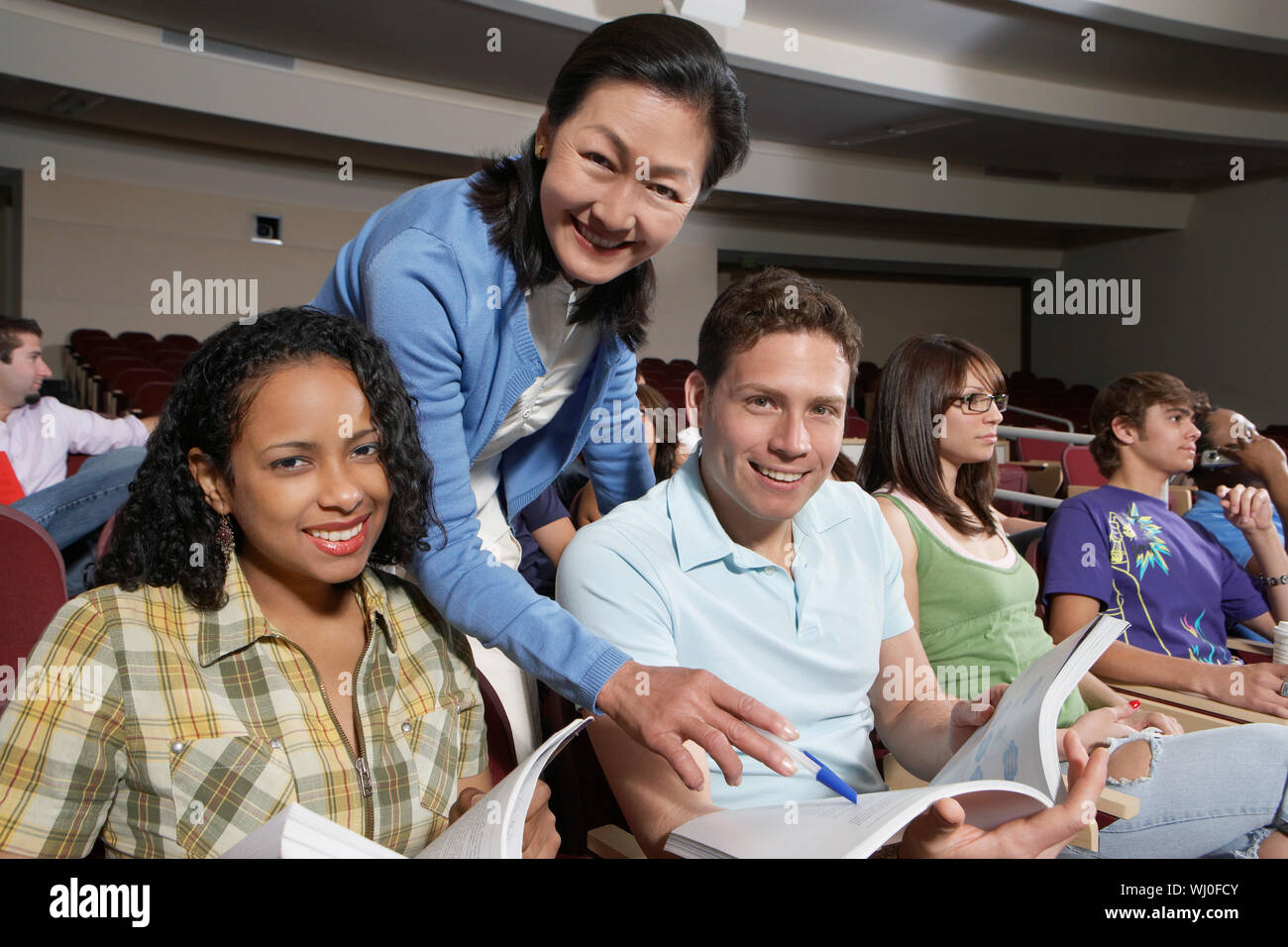 Female teacher assisting students in class, portrait Stock Photo - Alamy