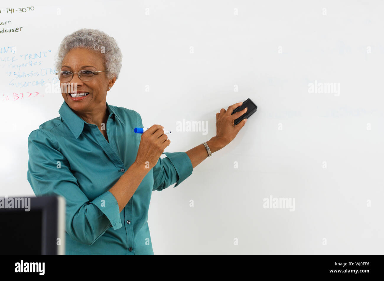 Female teacher erasing text on whiteboard in classroom Stock Photo - Alamy