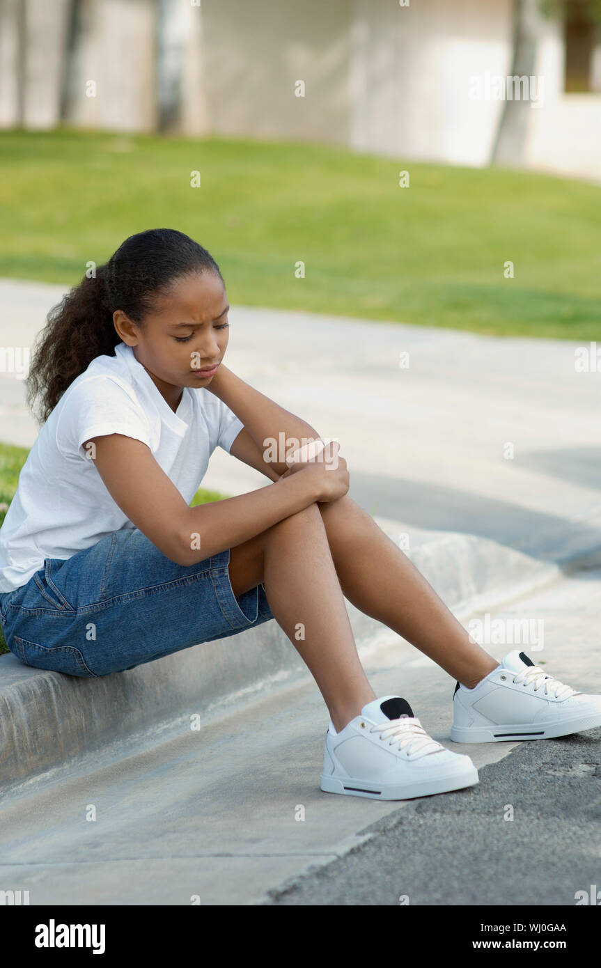 Girl (7-9) sitting on curb Stock Photo - Alamy