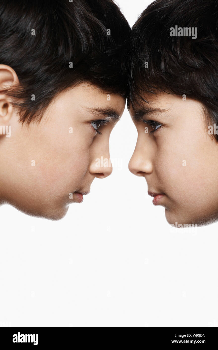 Side view closeup of preadolescent brothers with head to head isolated ...