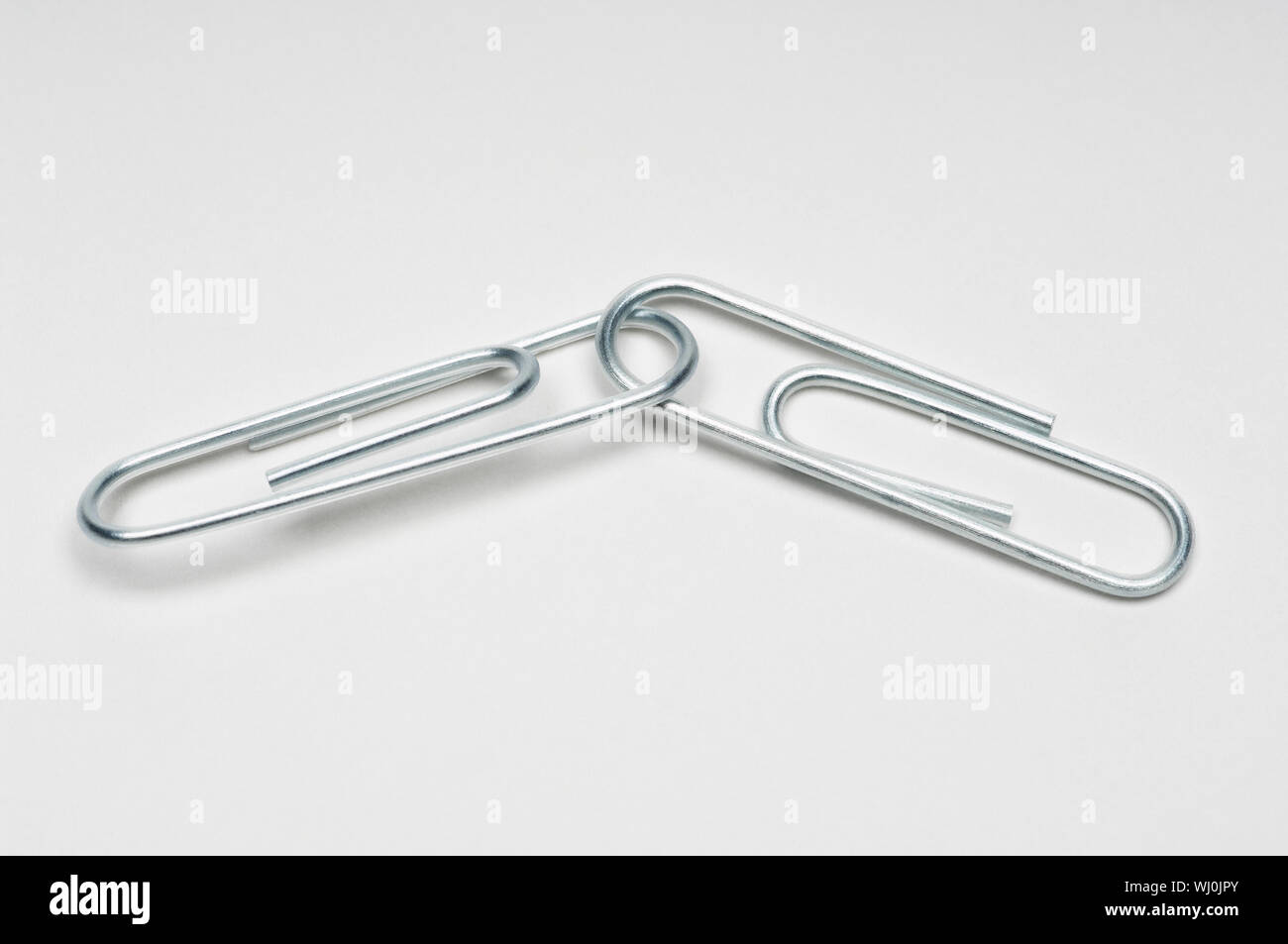 Two silver paper clips on white background Stock Photo - Alamy