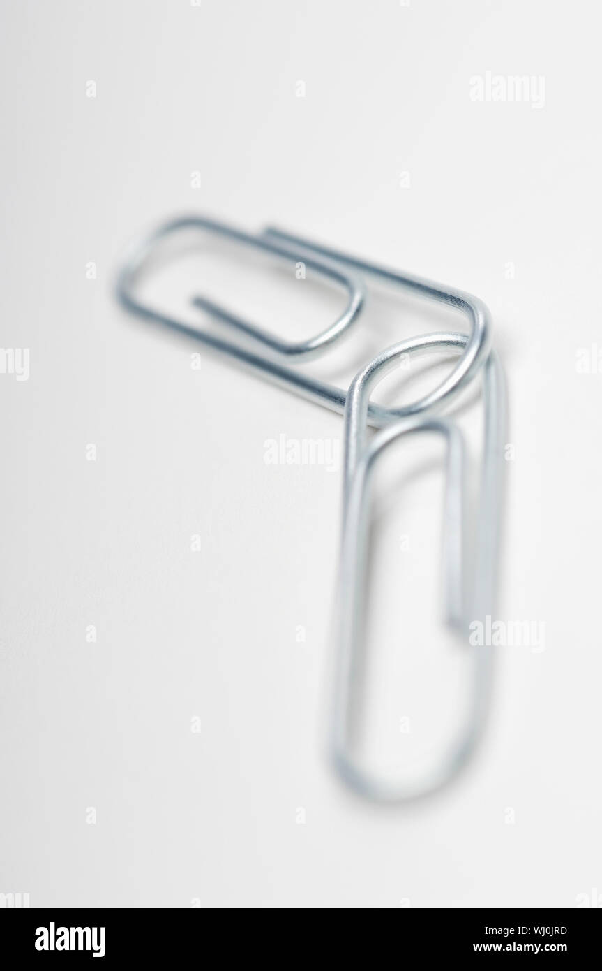 Two silver paper clips on white background Stock Photo - Alamy
