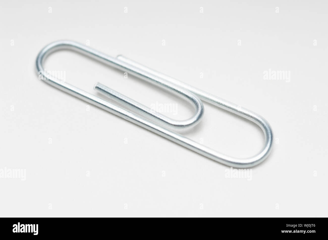 Silver paper clip on white background Stock Photo - Alamy