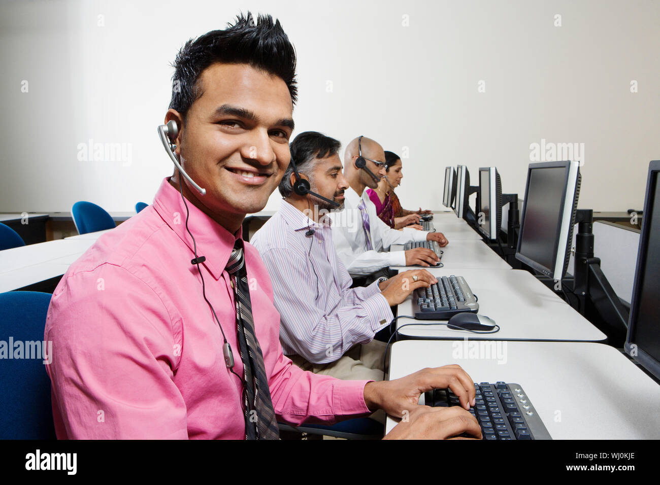 Portrait of a smart young customer service operator with colleagues in ...