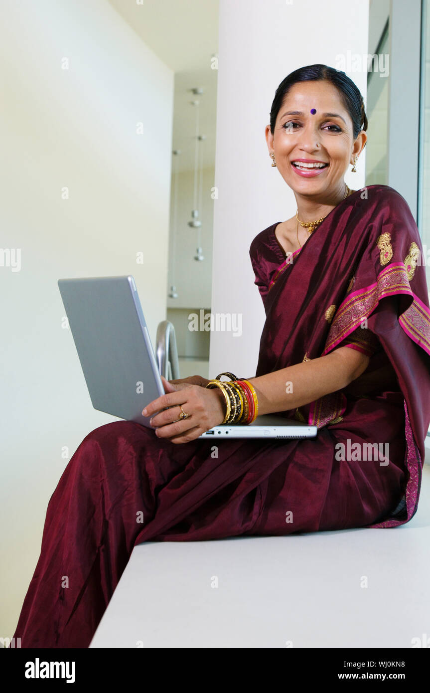 Portrait of a happy Indian business woman working on laptop at office ...
