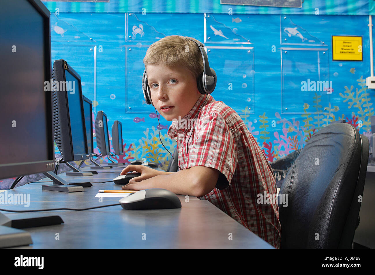 School boy wearing headphones in computer room Stock Photo - Alamy