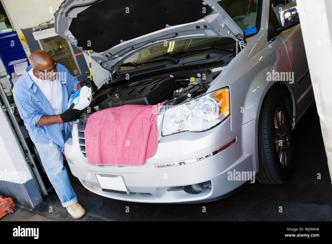 An African American male mechanic oiling car's engine at garage Stock ...