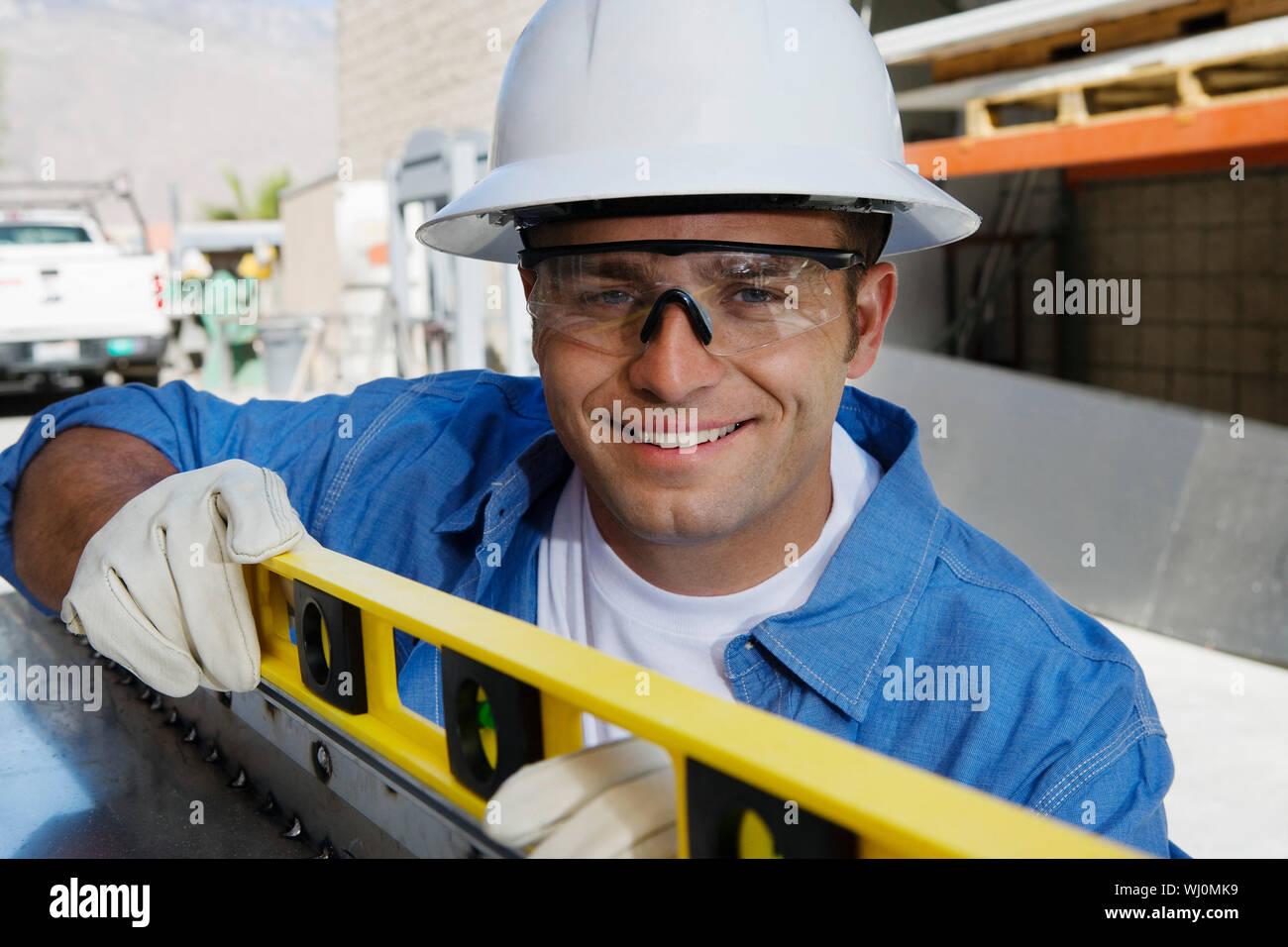 A happy middle aged male industrial worker holding yellow level Stock ...