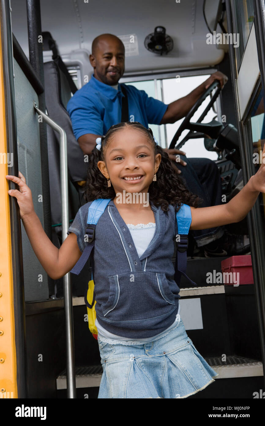 Portrait of a cute little girl getting down from the bus while driver ...