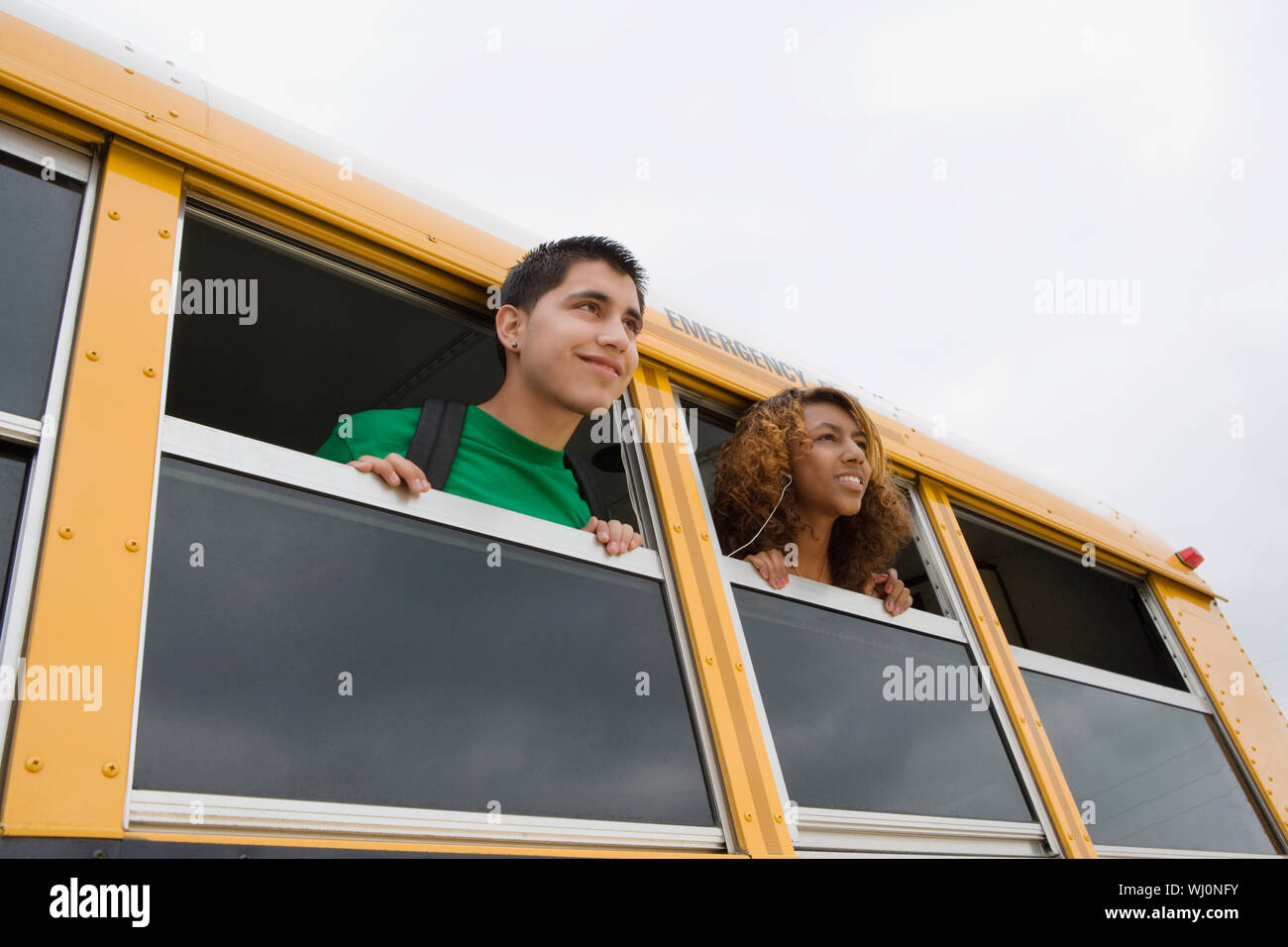 Low angle view of two happy students looking through window of a school ...
