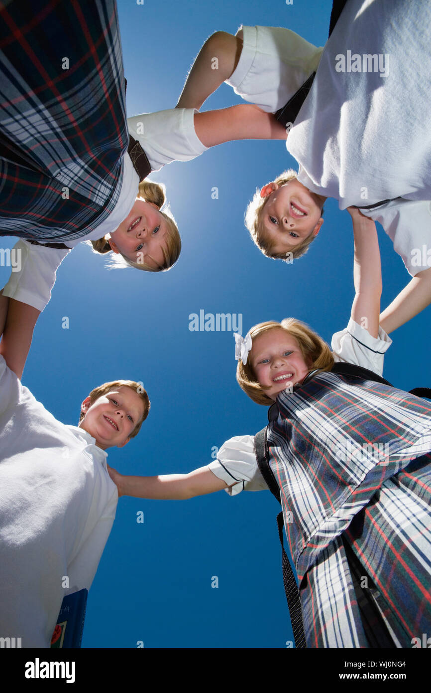 Happy school friends forming huddle together against blue sky Stock ...