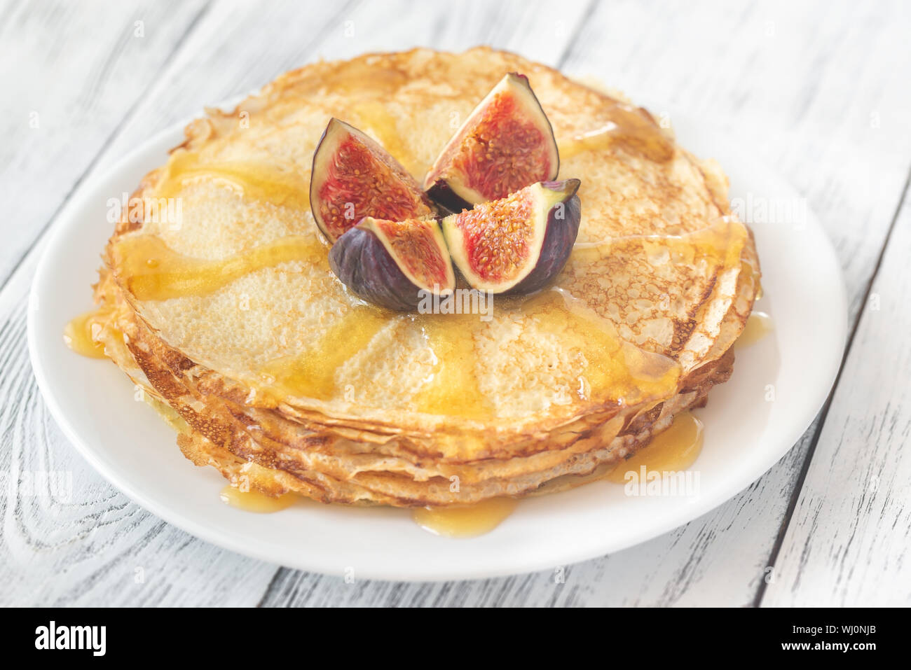 Stack of homemade crepes with fresh fig and sweet topping on the white ...