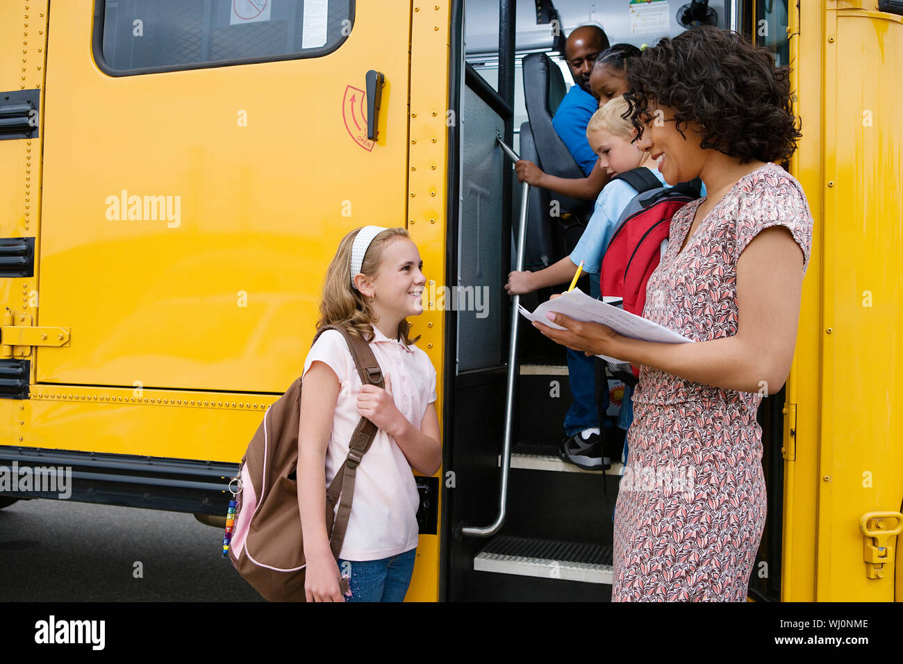 Happy female teacher looking at student as she boards school bus Stock ...