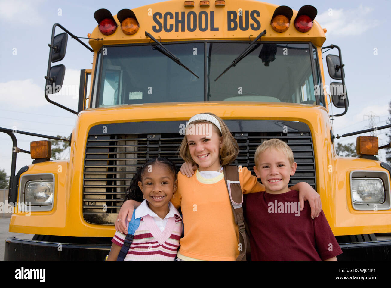 Portrait of happy friends standing in front of school bus Stock Photo ...