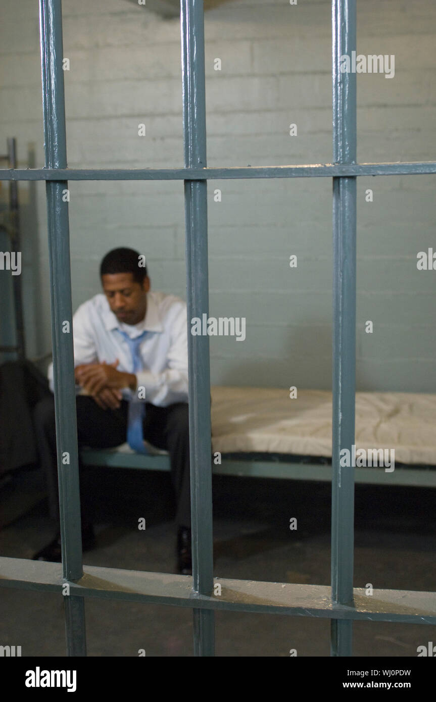 Man sitting in prison cell Stock Photo - Alamy