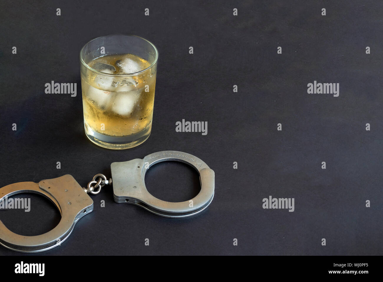 Alcohol and handcuffs on black color background. Alcoholism, law ...