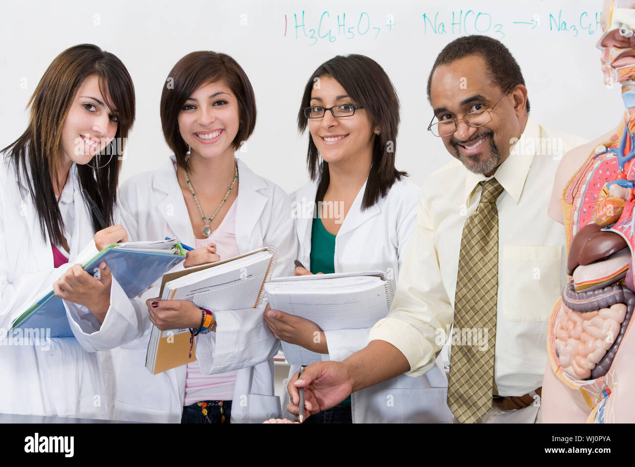 Portrait of science professor with female students in science class ...