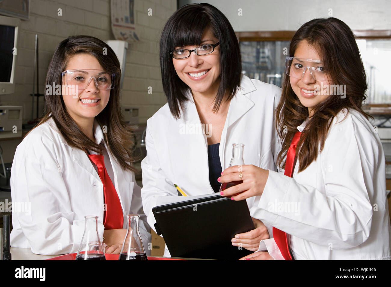 Female students experimenting while professor writing notes in ...