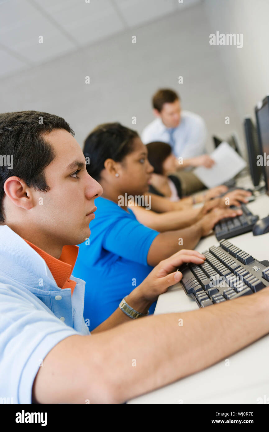 Multiethnic students using computer with professor in lab Stock Photo ...