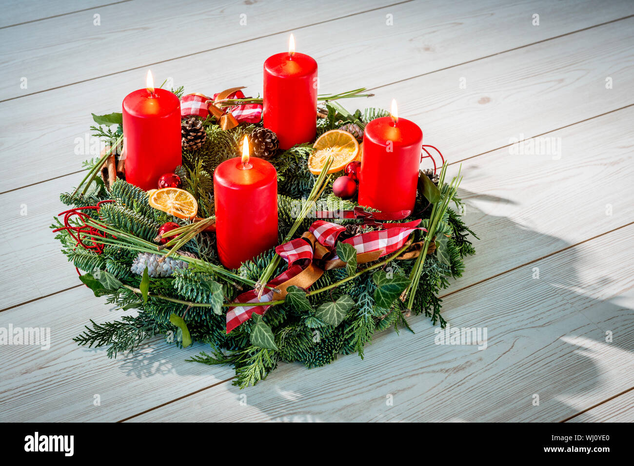 Advent wreath of twigs with four burning red candles and various ...