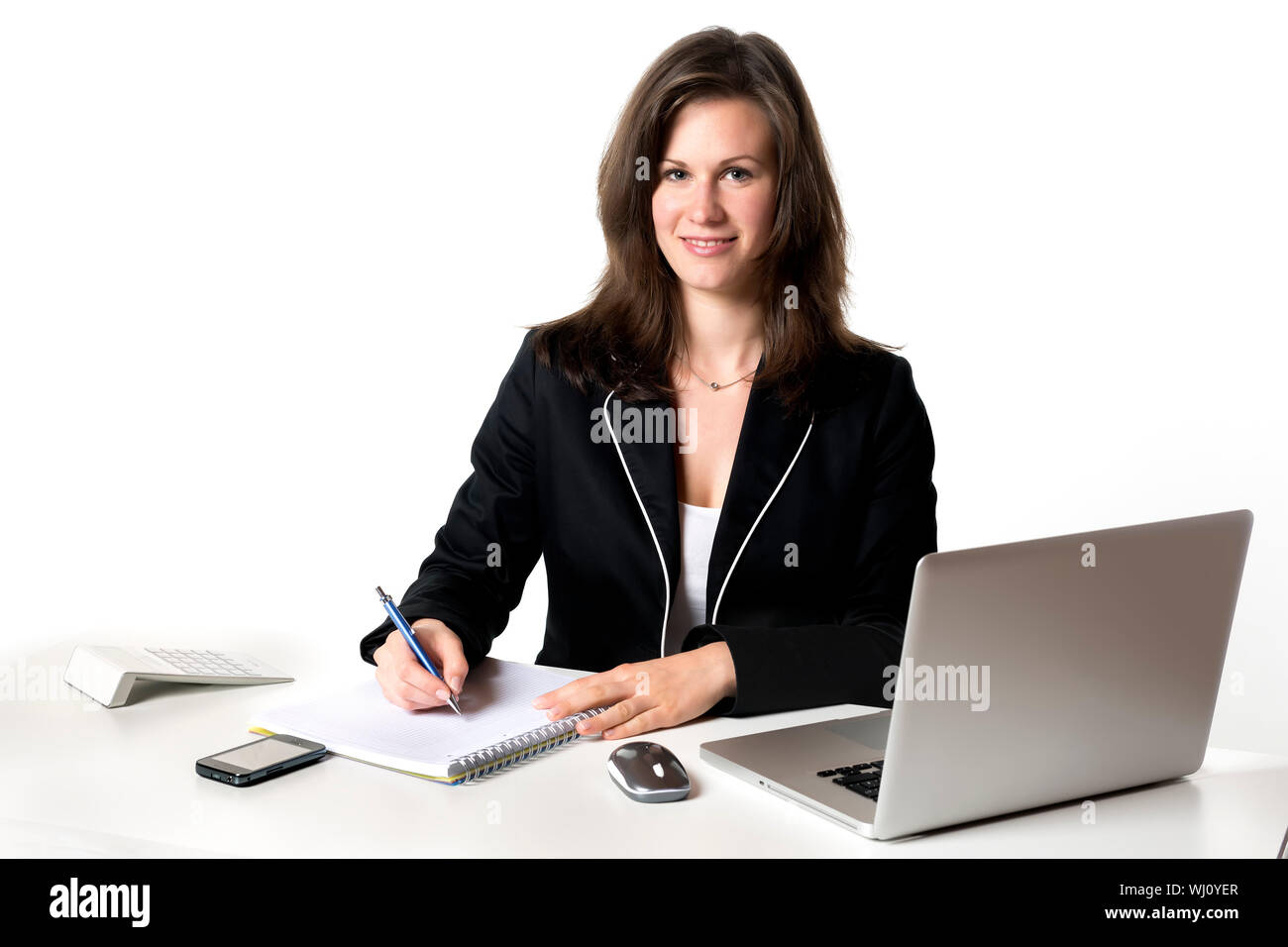Smiling Businesswoman sitting at desk in office, writing something on a ...