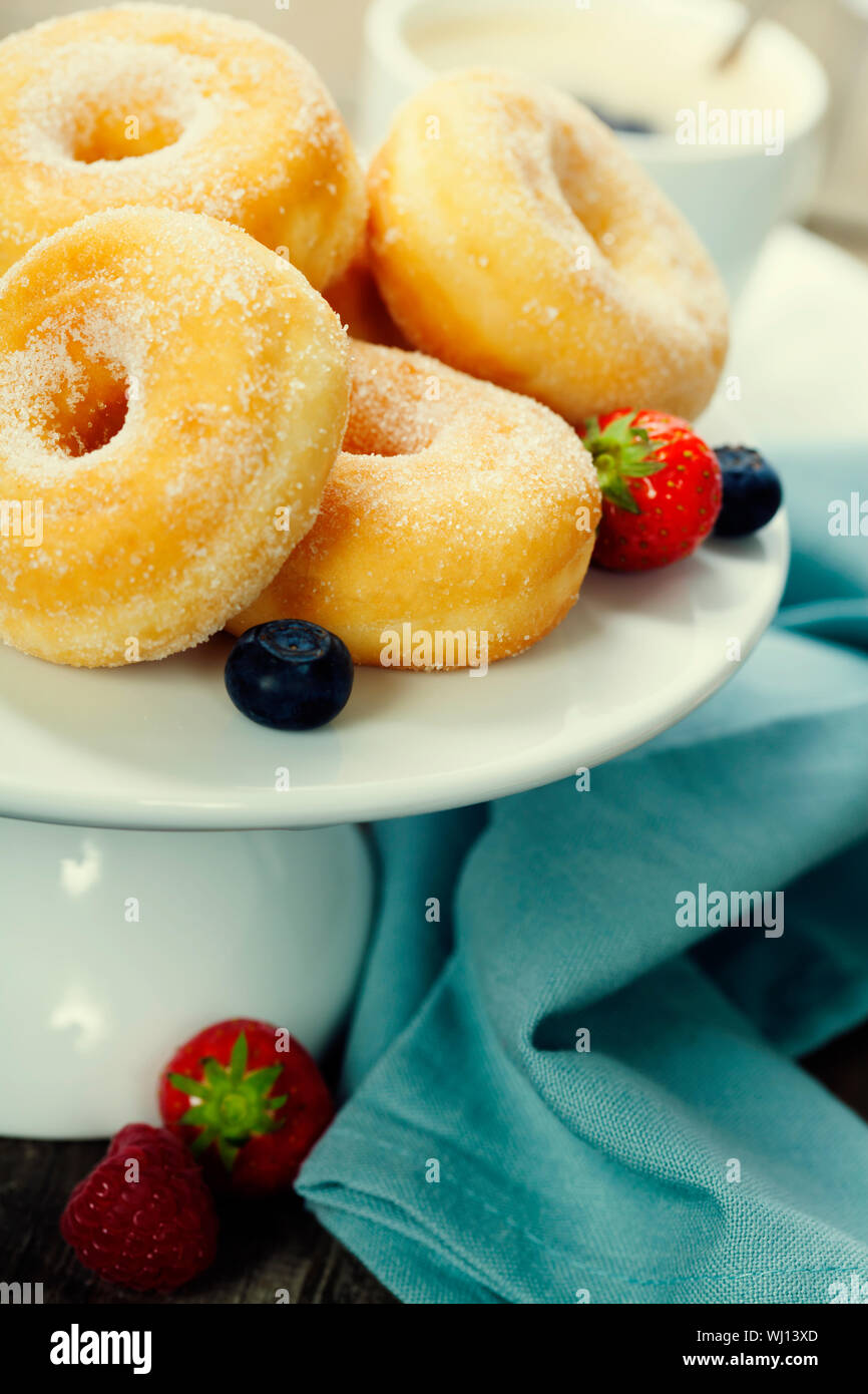Coffee break with fresh berries and sugary donuts over white background ...