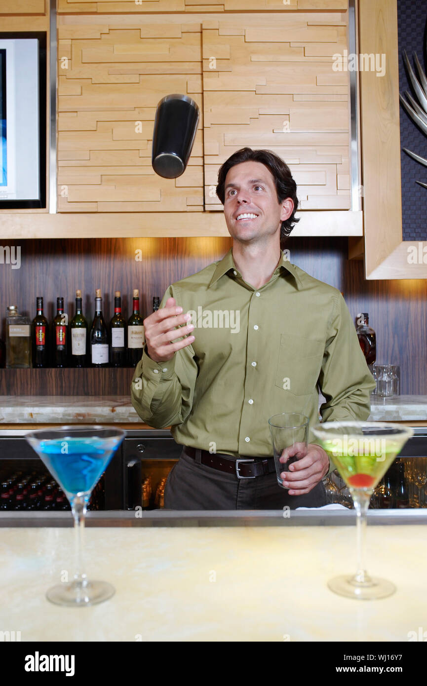 Handsome bartender mixing mocktail drink in shaker at bar counter in ...