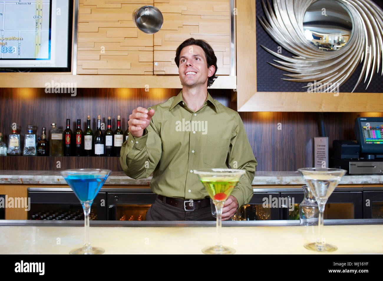 Mature handsome barman mixing cocktail drink in shaker at bar counter ...